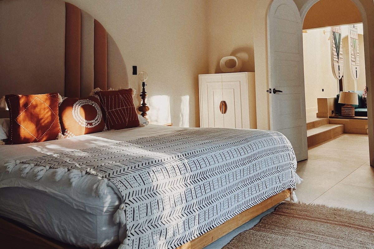 Quarto com uma cama grande, um guarda-roupa e uma cesta suspensa.