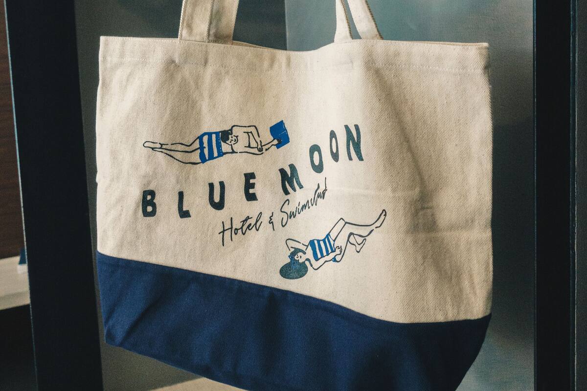 Uma bolsa bege e azul pendurada em uma estante de metal preta.