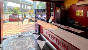 Uma área de recepção com balcão de check-in, piso estampado e vista para o estacionamento externo.