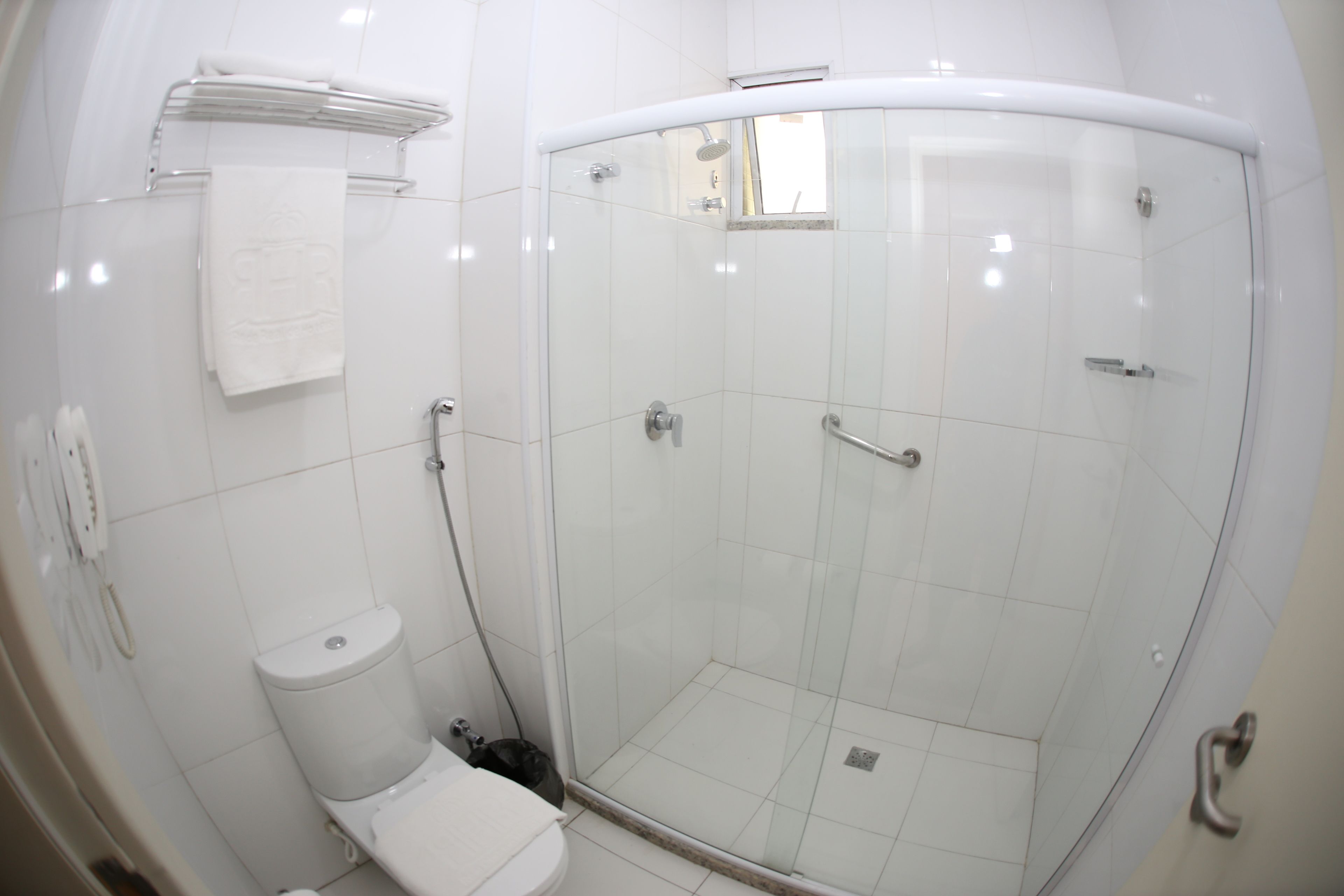 Uma casa de banho moderna com chuveiro envidraçado, sanita e um porta-toalhas.