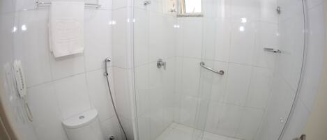 Uma casa de banho moderna com chuveiro envidraçado, sanita e um porta-toalhas.