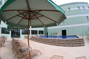 Uma área de piscina com espreguiçadeiras e um espaço de estar coberto.