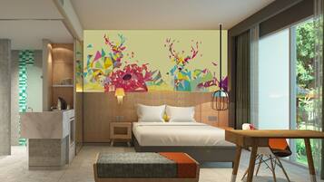 Quarto de hotel moderno com uma cama grande, uma escrivaninha de madeira, um banco, uma obra de arte abstrata colorida na parede, um banheiro e uma janela ampla com vista para o verde.
