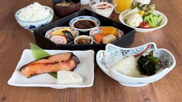 Uma refeição tradicional japonesa com arroz, peixe, legumes e diversos acompanhamentos sobre uma mesa de madeira.