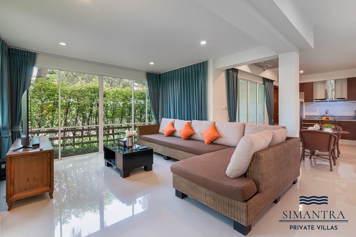 Uma sala de estar moderna com sofá, mesa de centro e vista para o verde lá fora.