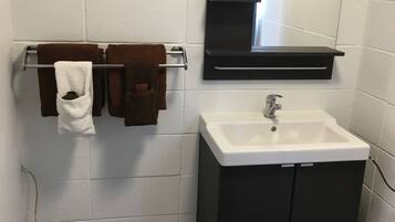 Uma casa de banho com uma pia branca, armários escuros, um porta-toalhas com toalhas castanhas e um espelho sobre a pia.