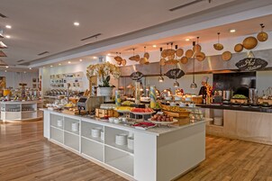 Buffet montado com diversos alimentos e um chef ao fundo.
