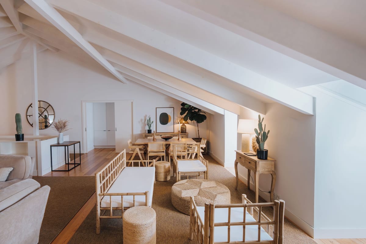 Um loft espaçoso com pé direito alto, sala de jantar e um espaço de estar aconchegante com um banquinho redondo.