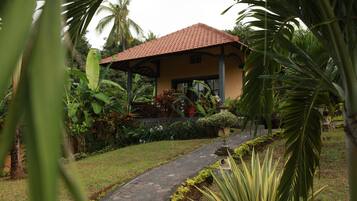 Um edifício com telhado de azulejos, rodeado por vegetação exuberante e um caminho de pedra.