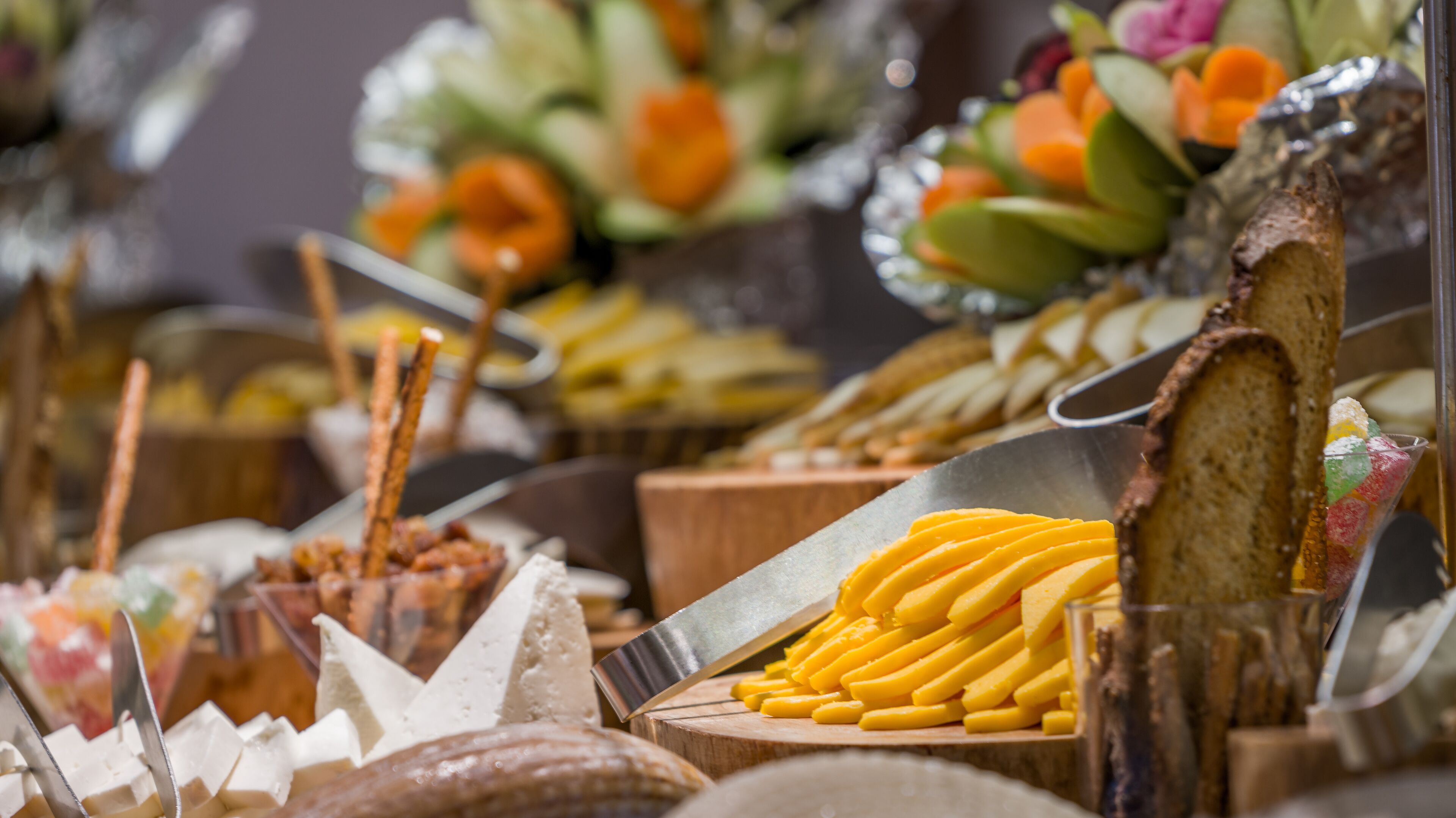Buffet com diversos alimentos, incluindo queijo, frutas e pão.