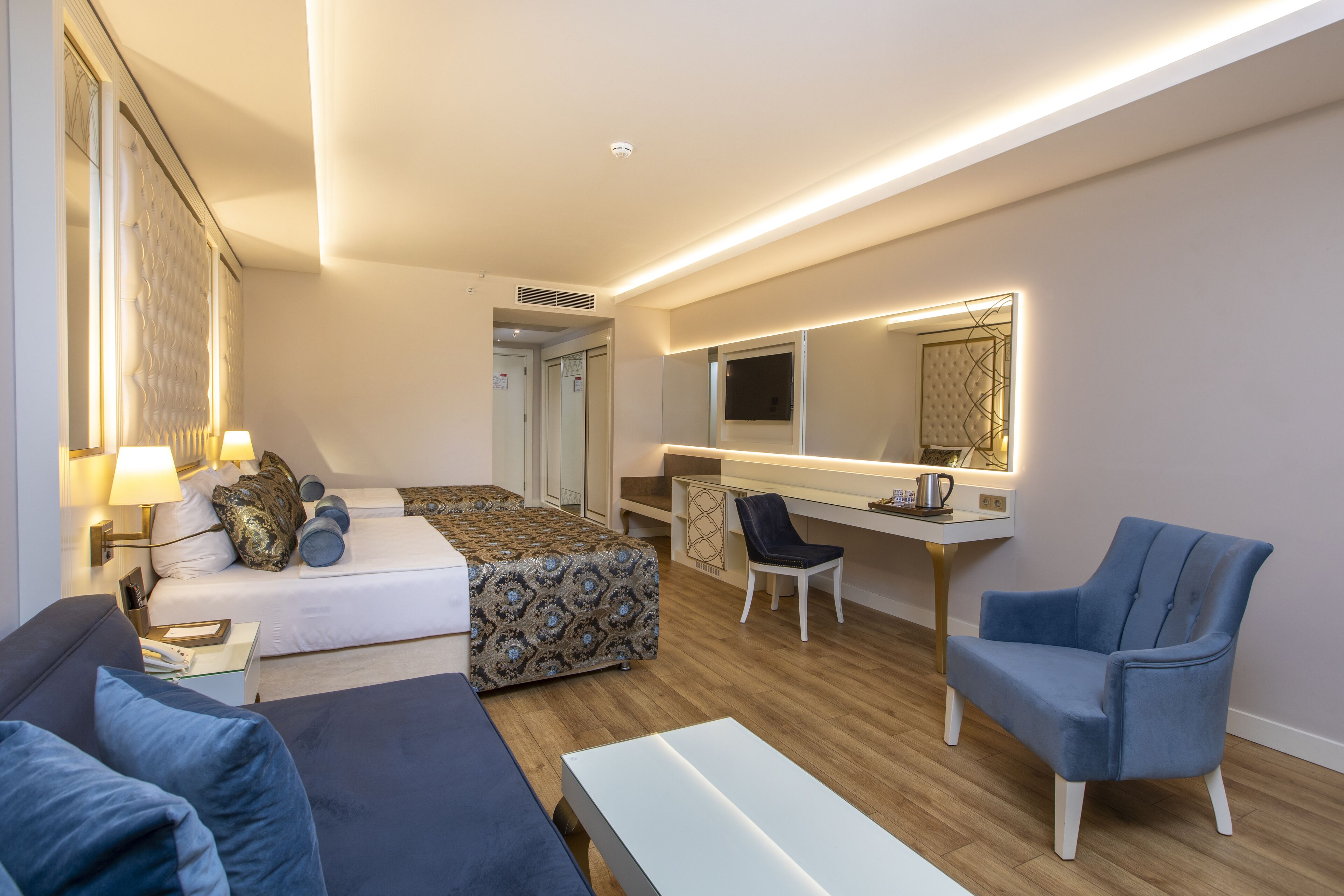 Quarto de hotel moderno com cama, escrivaninha, cadeira e sofá.