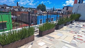 Terraço no telhado com piscina, plantas em vasos e piso de azulejos.