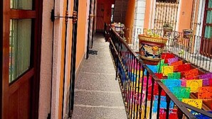 Um corredor com teto de vidro, porta de madeira e detalhes coloridos no corrimão.