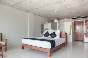 Quarto moderno com cama de madeira, paredes brancas e teto de concreto.