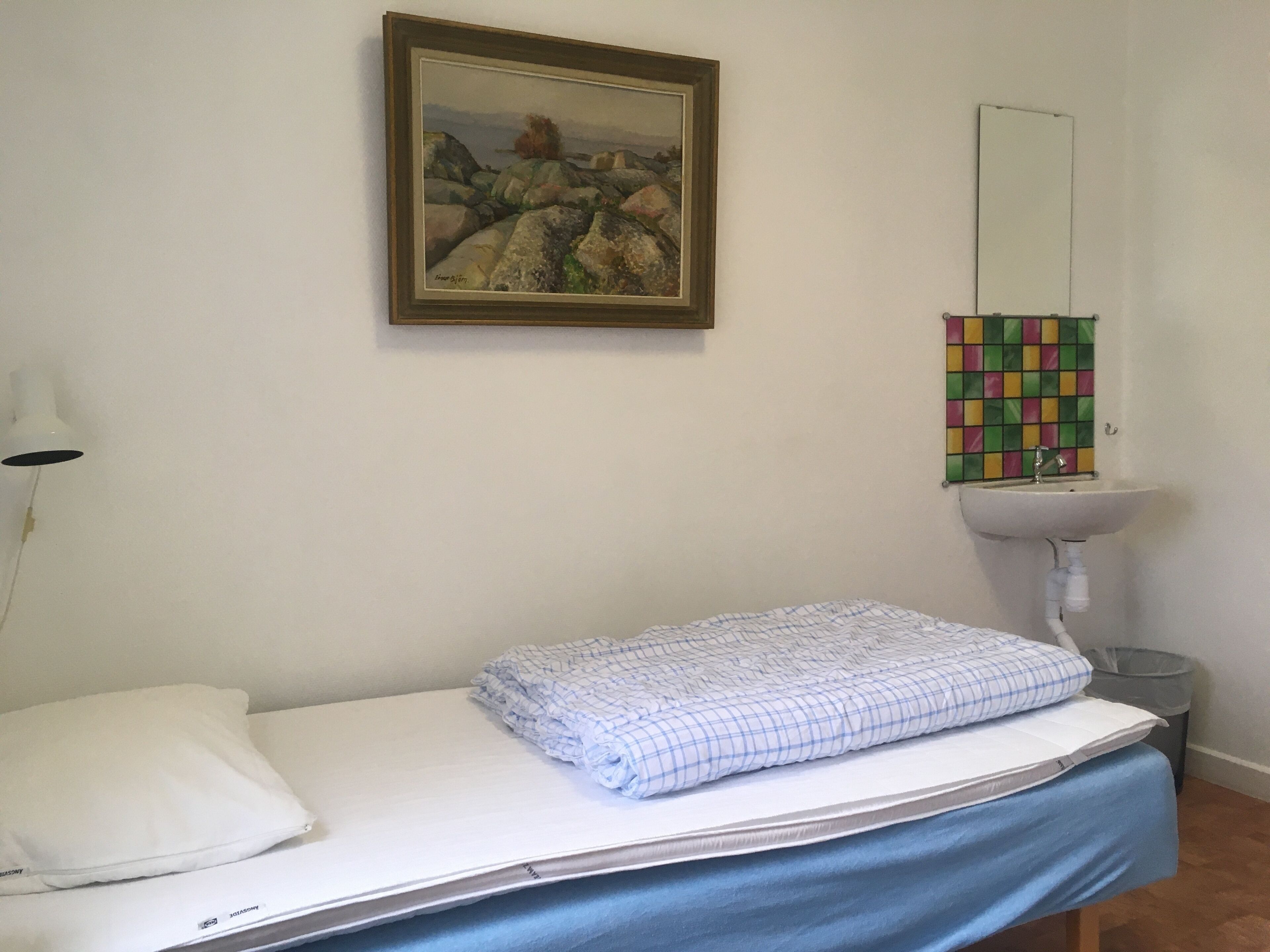 Quarto com cama, pintura, pia e espelho.