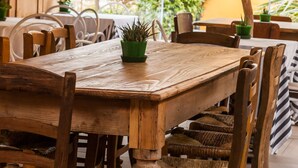 Uma mesa de jantar de madeira com cadeiras, uma planta em vaso e luminárias pendentes.