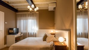 Quarto de hotel com cama, escrivaninha, televisão, mesa de cabeceira e um espelho grande.