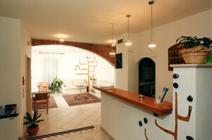 Um saguão de hotel com balcão de recepção, área de estar e vista para uma sala de jantar.