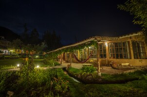 Área externa bem iluminada com um alpendre, assentos e uma rede.