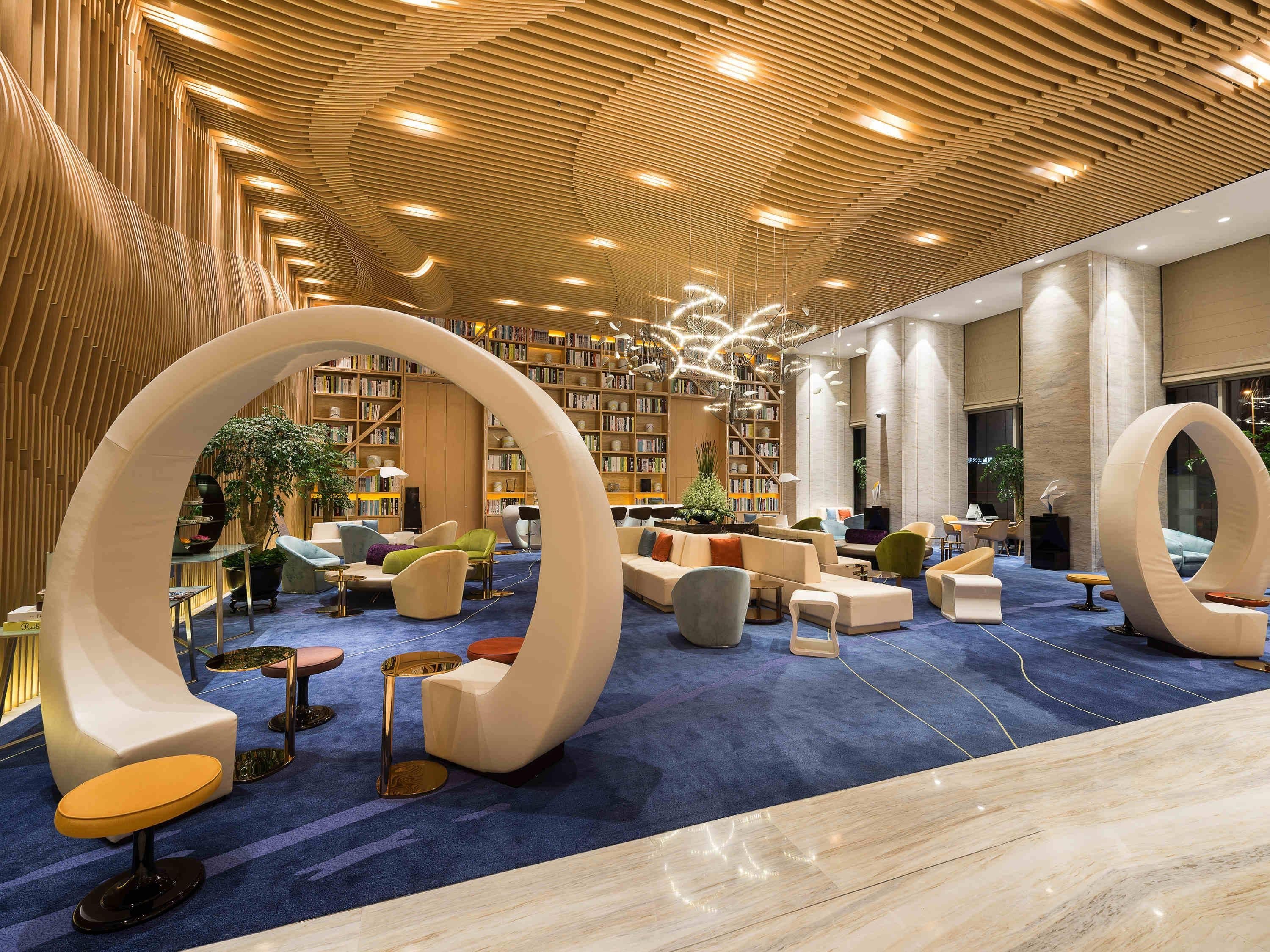 Uma biblioteca moderna com áreas de estar curvas, estantes e um design de teto singular.