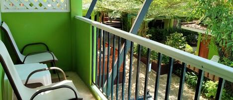 Uma varanda com piscina, paredes verdes e cadeiras brancas.