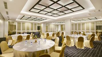 Uma sala de conferência com mesas redondas, cadeiras e um teto alto com padrão de grade.