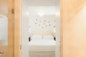 Quarto de hotel com cama, lustre e adesivos de parede em formato de estrela.