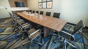 Uma sala de conferência com uma mesa comprida, cadeiras e uma televisão na parede.