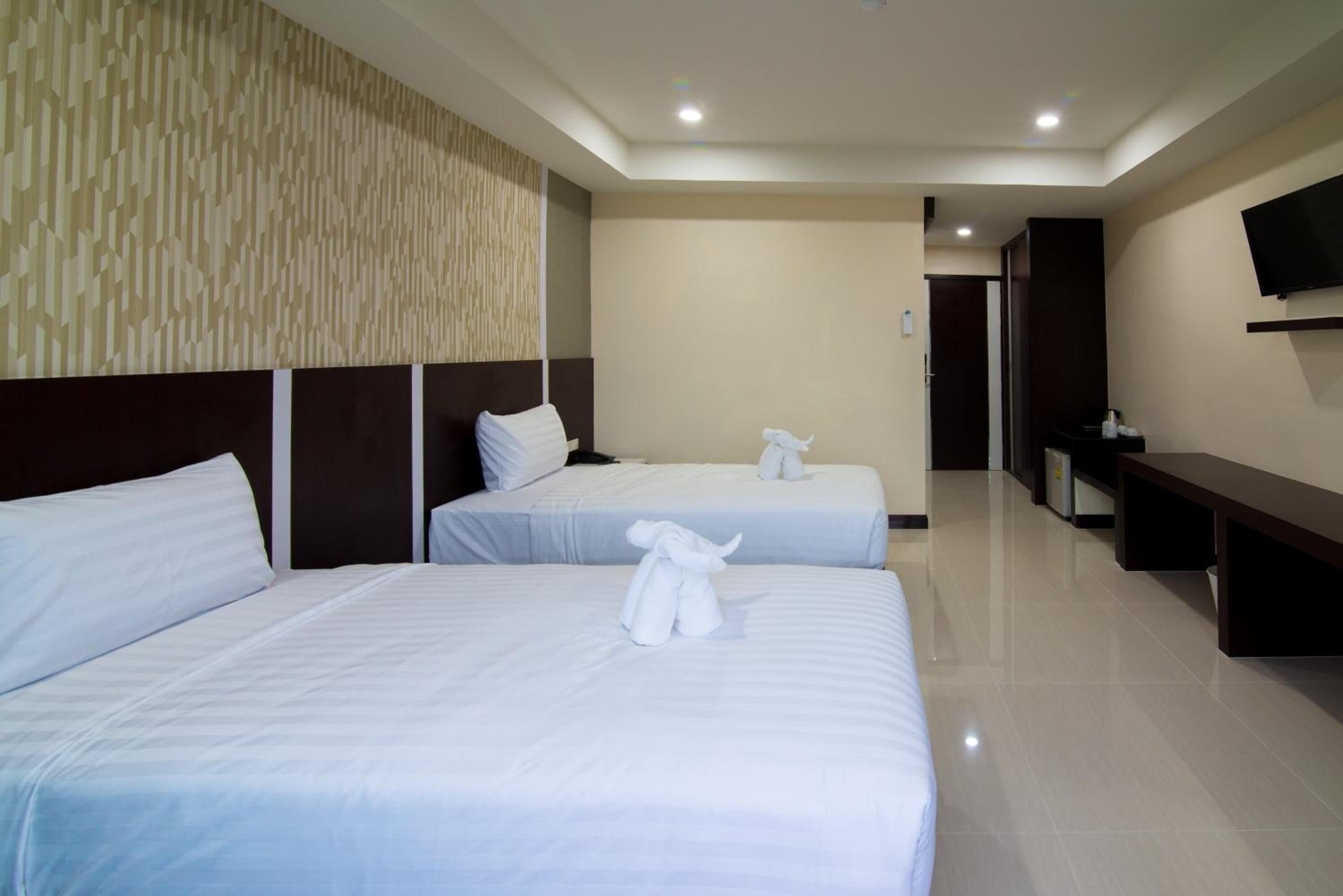Quarto de hotel com duas camas, televisão de tela plana e um banco.