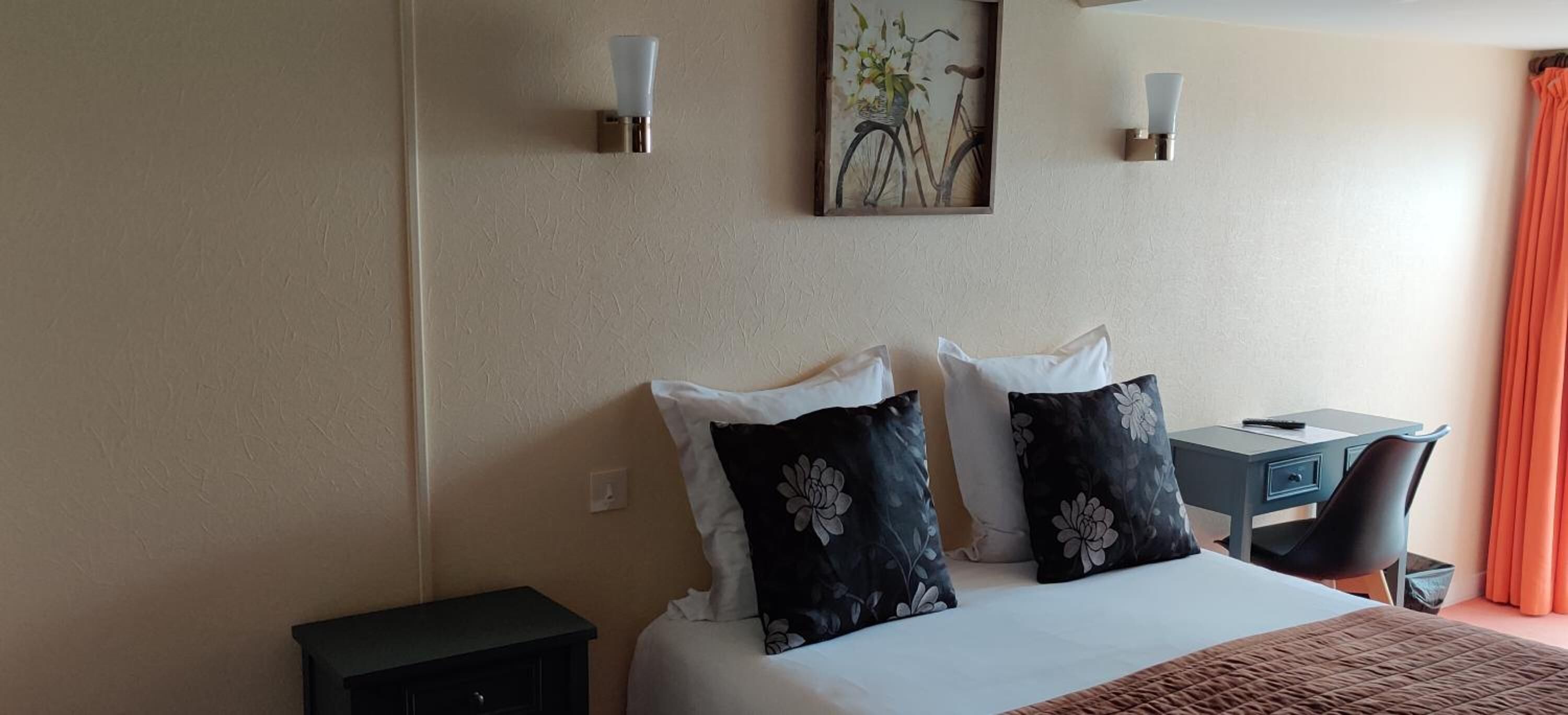 Quarto de hotel com uma cama, duas mesas de cabeceira, uma escrivaninha e uma cadeira.