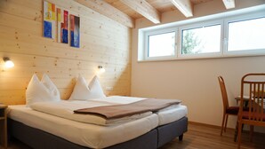 Um quarto com painéis de madeira, uma cama, uma cadeira e uma janela.