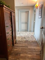 Um corredor com um armário de madeira, um tapete estampado e uma porta no final.