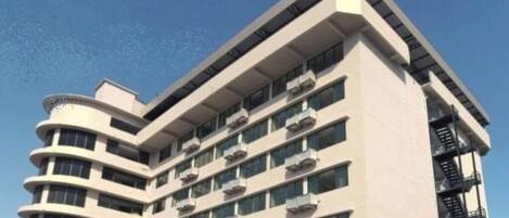 Um edifício de vários andares com fachada curva, aparelhos de ar condicionado e uma série de varandas.
