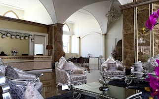 Um hall de entrada luxuoso com móveis requintados, um espelho imponente e um candelabro.