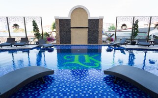 Piscina com piso azulejado e parede decorativa no centro.