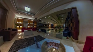 Um hall amplo com design moderno, com área de recepção, assentos e uma parede decorativa.