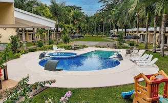 Área da piscina com espreguiçadeiras e um parquinho infantil.