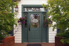 Uma porta dupla verde com uma placa de 'Bem-vindo' e uma placa que diz 'The Historic Elk Mountain Hotel'.