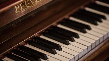 Um close-up de um piano com teclas pretas e brancas, e a marca "REYEL" visível na lateral.