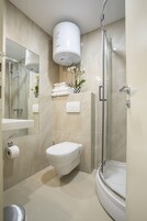 Uma casa de banho moderna com sanita, lavatório e chuveiro.