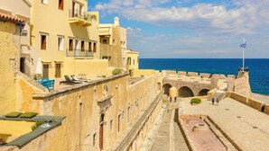 Uma vila costeira com arquitetura histórica, uma muralha fortificada e um mastro.