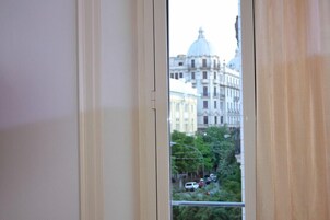 Janela com vista para um horizonte urbano, incluindo um edifício grande com cúpula e vários edifícios menores.