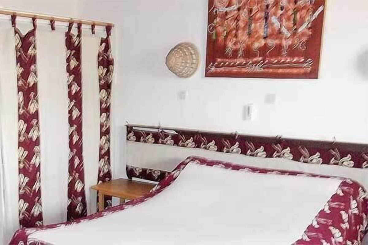 Um quarto com uma cama, um espelho, um guarda-roupa e um quadro na parede.