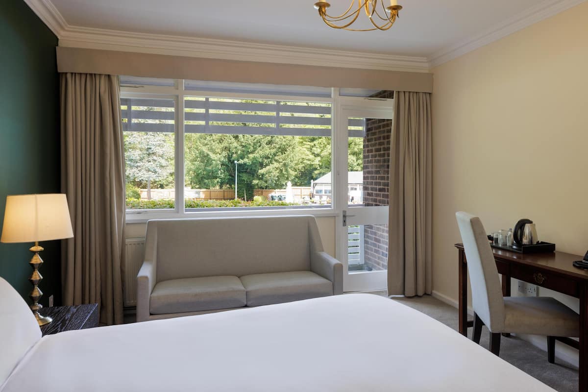 Quarto de hotel com uma cama grande, um sofá, uma escrivaninha e vista para o exterior.