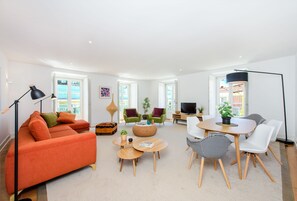 Uma sala de estar moderna com sofá, mesa de centro, cadeiras e televisão.