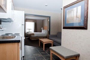 Quarto de hotel compacto com cozinha compacta, cama, mesa pequena e sofá.