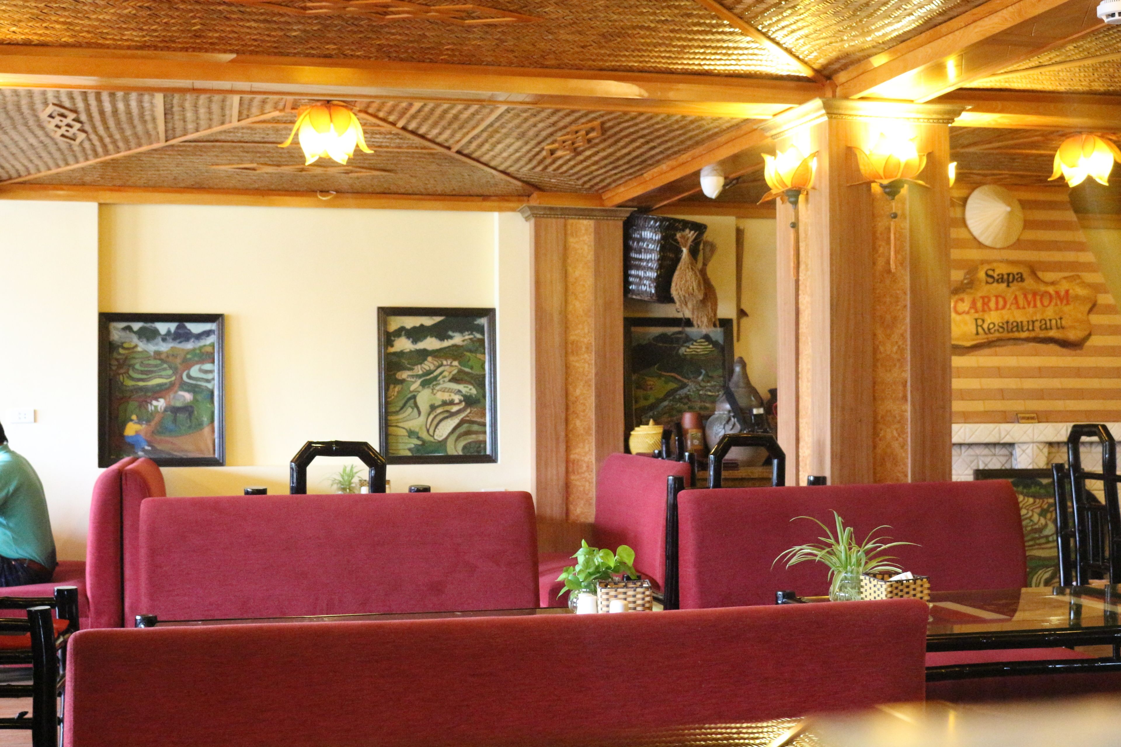 Interior de restaurante com assentos em cabines estofadas de vermelho, teto de madeira e obras de arte penduradas nas paredes.
