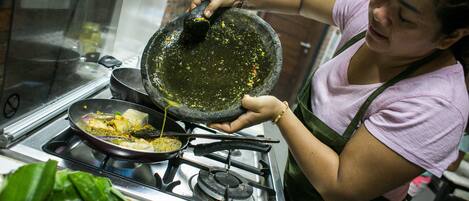 Uma pessoa cozinhando em um fogão, segurando uma frigideira com comida.