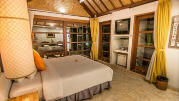 Um quarto com cama, cortinas, televisão e escrivaninha.