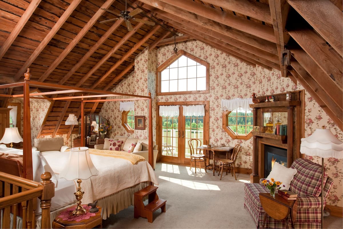 Um quarto de sótão acolhedor com uma cama de dossel, lareira e um espaço de refeições.